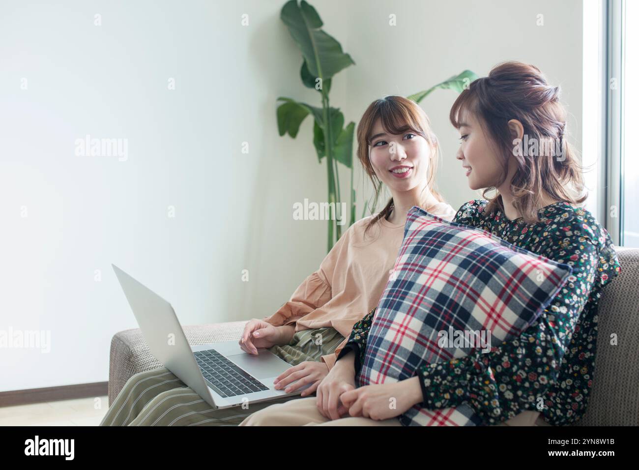 Two smiling women in their 20s looking at a computer Stock Photo - Alamy