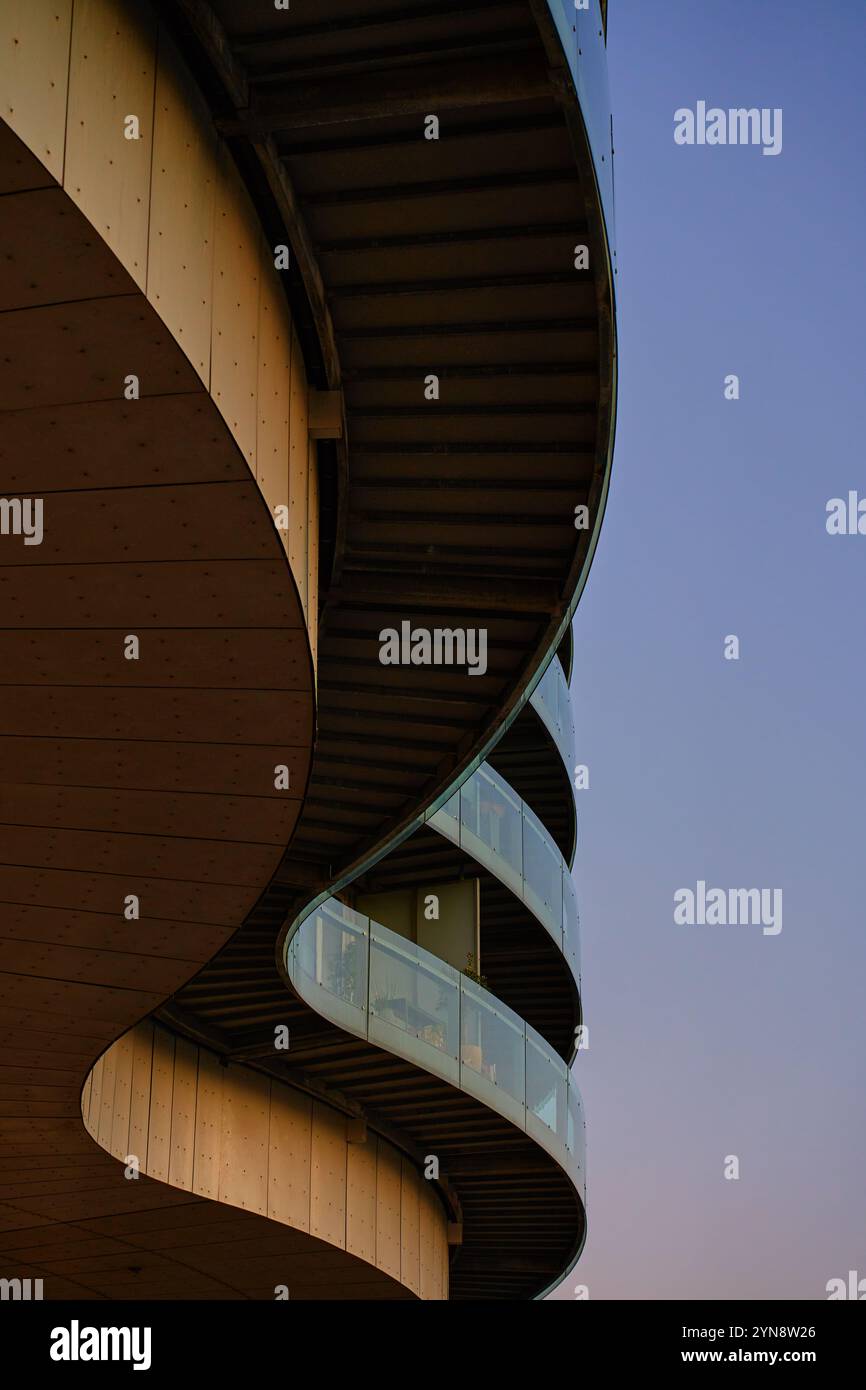 Modern round residential building with balconies at sunset ...