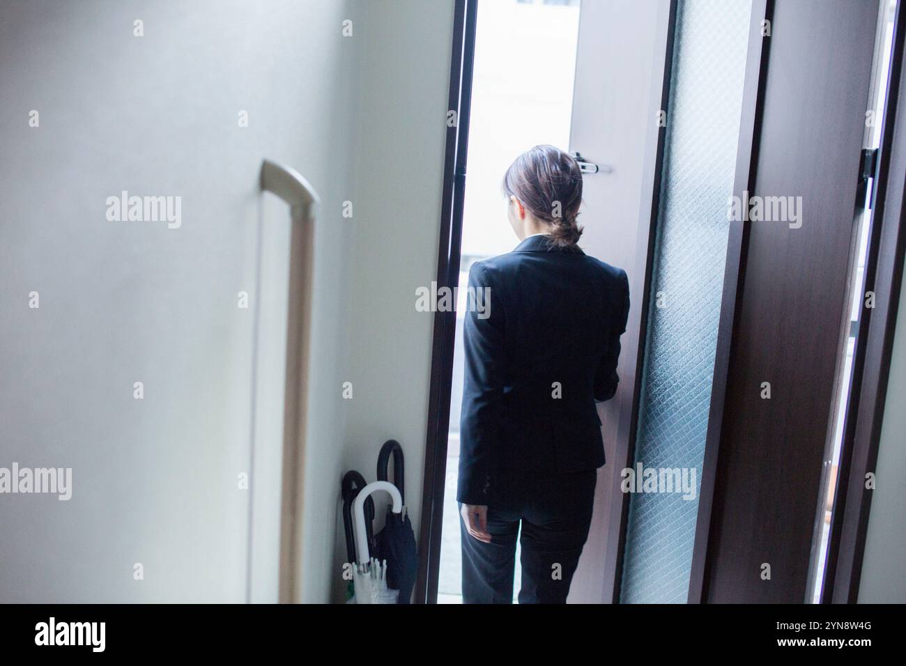 Back view of woman in her 20s opening front door Stock Photo - Alamy