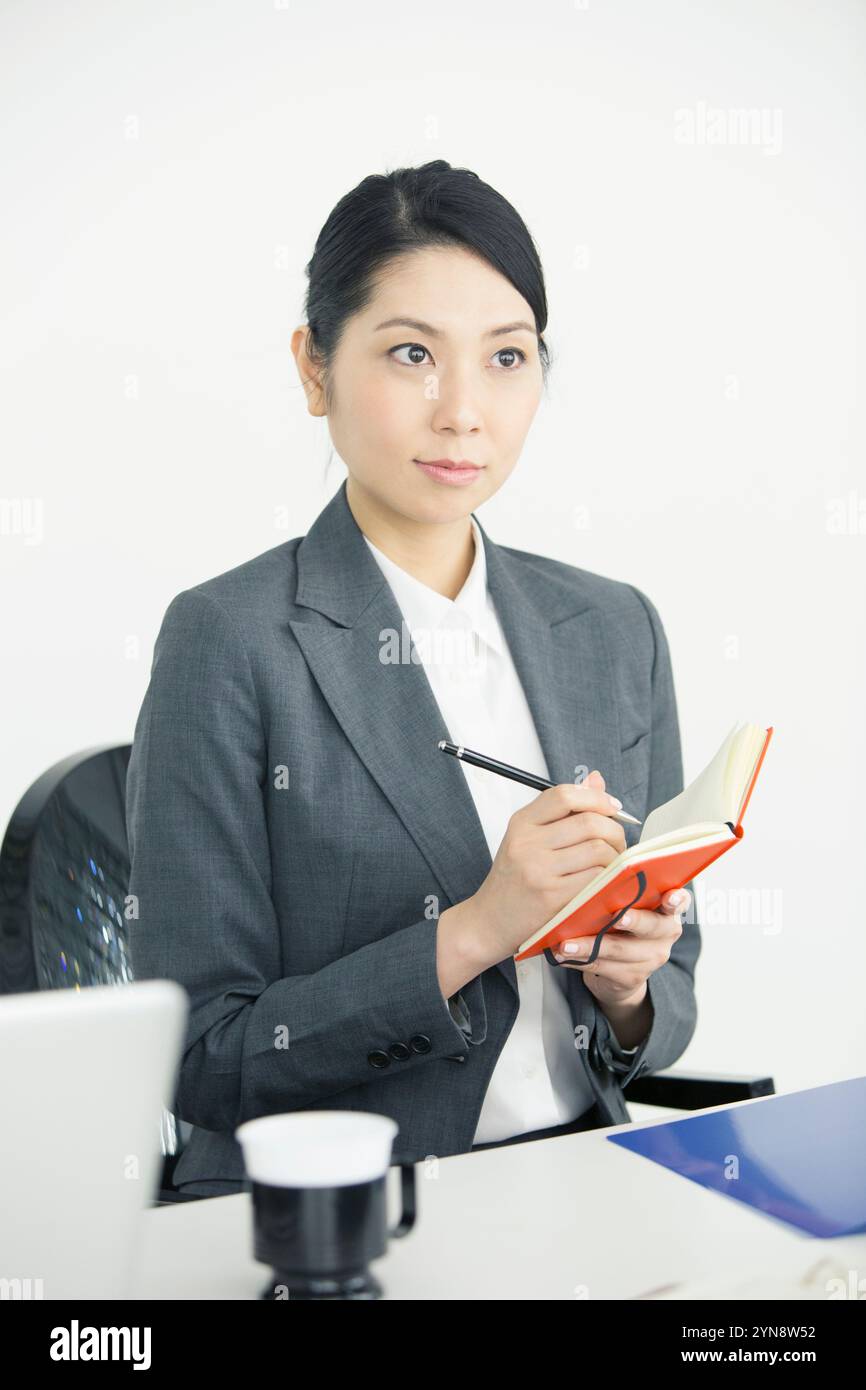 Serious-looking woman in her 30s taking notes at work Stock Photo - Alamy