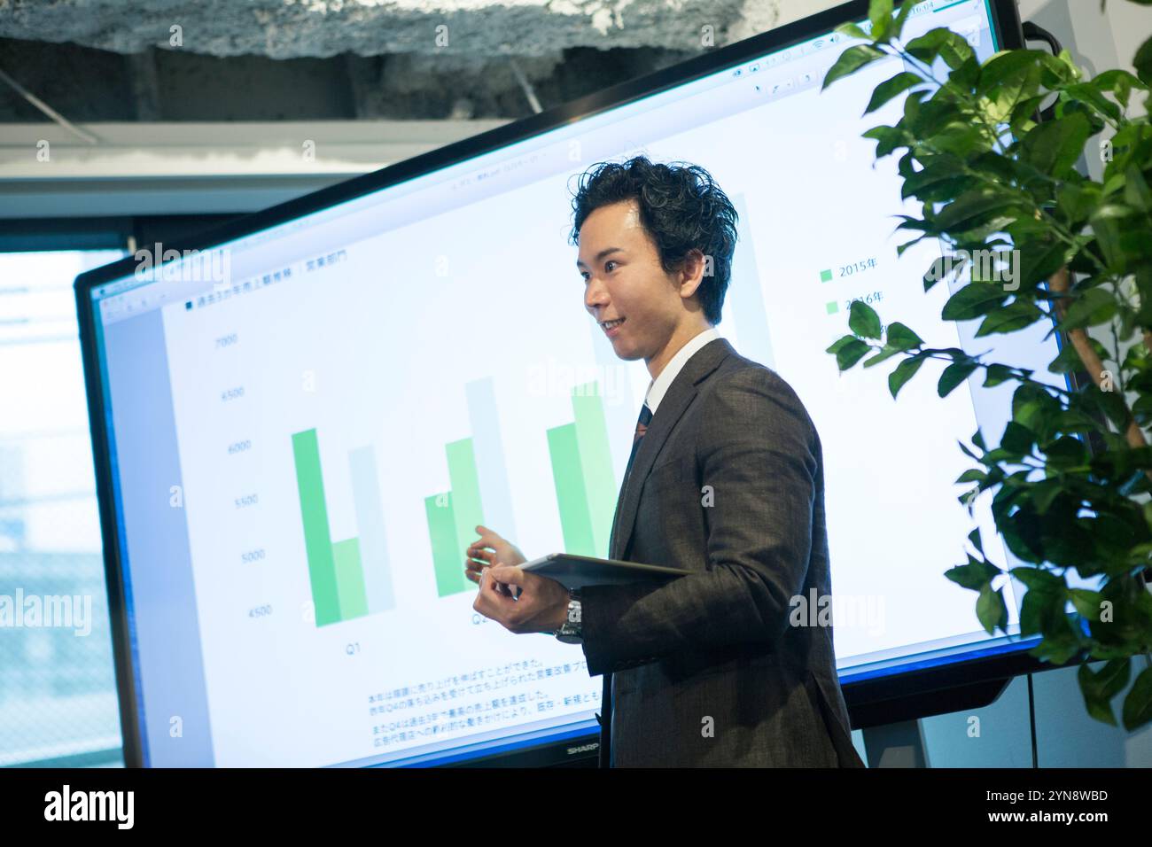 Smiling man in his 20s showing and explaining a graph Stock Photo - Alamy