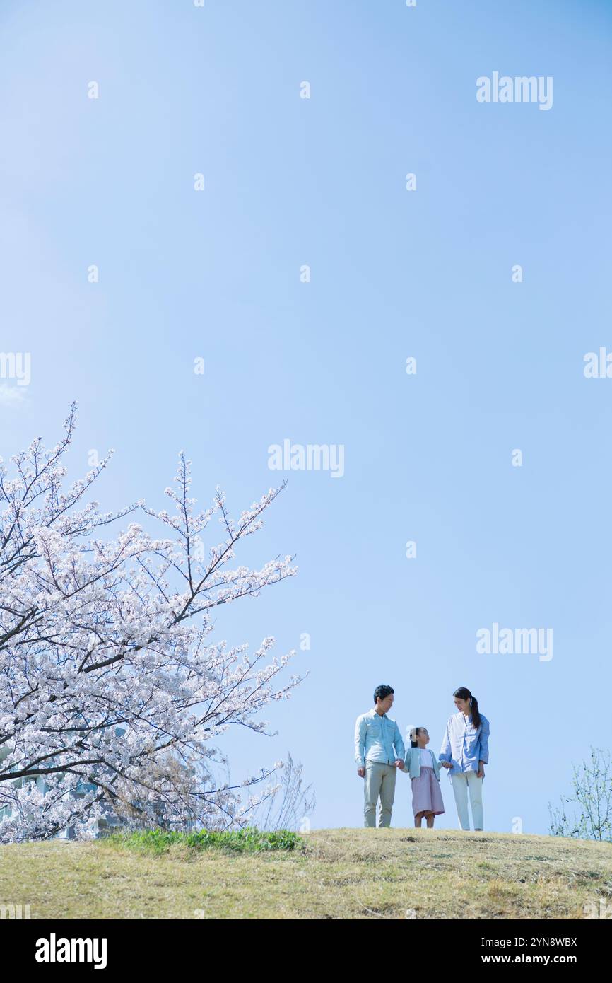 Happy family standing under a cherry tree Stock Photo - Alamy