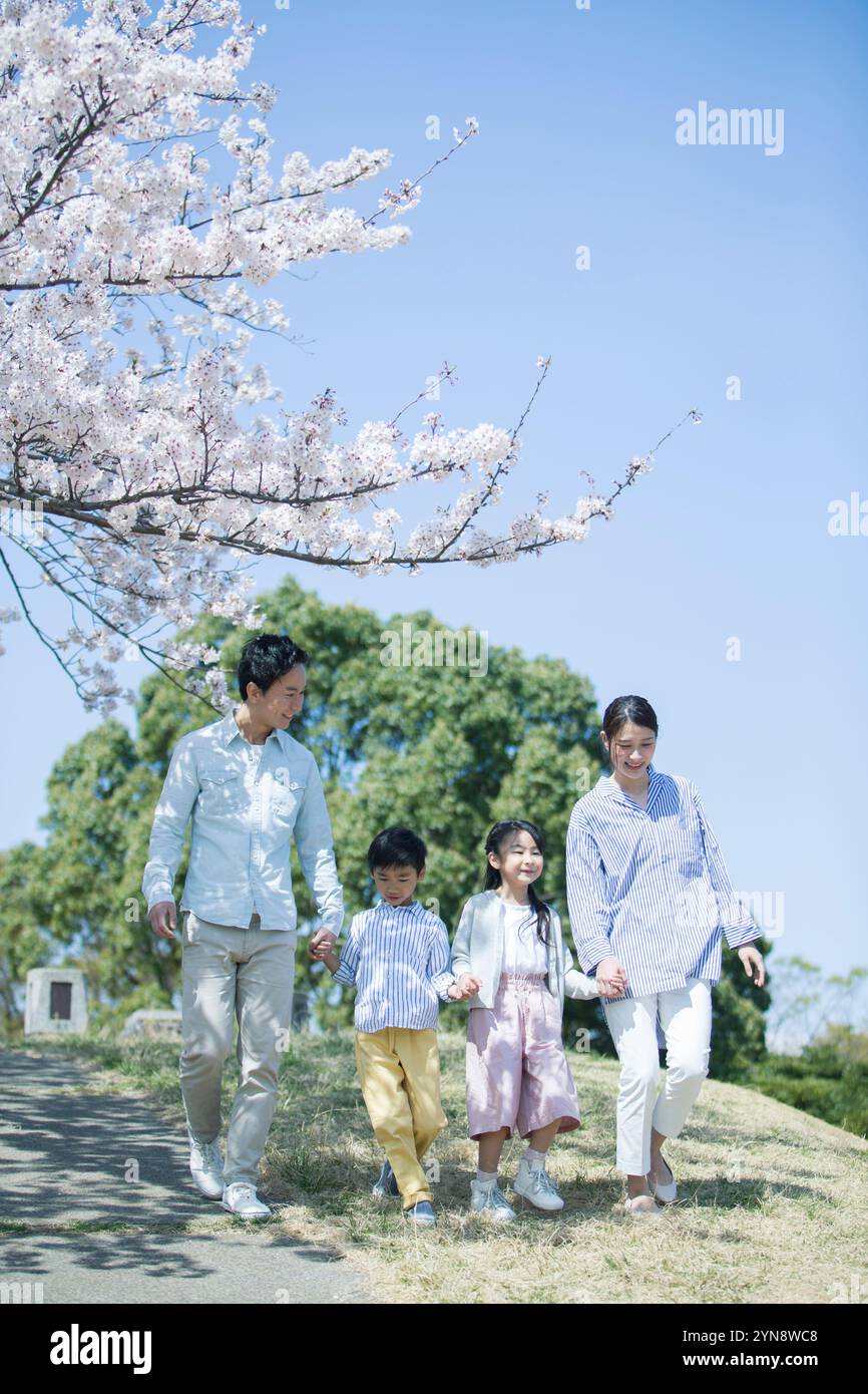 Happy family walking under a cherry tree Stock Photo - Alamy