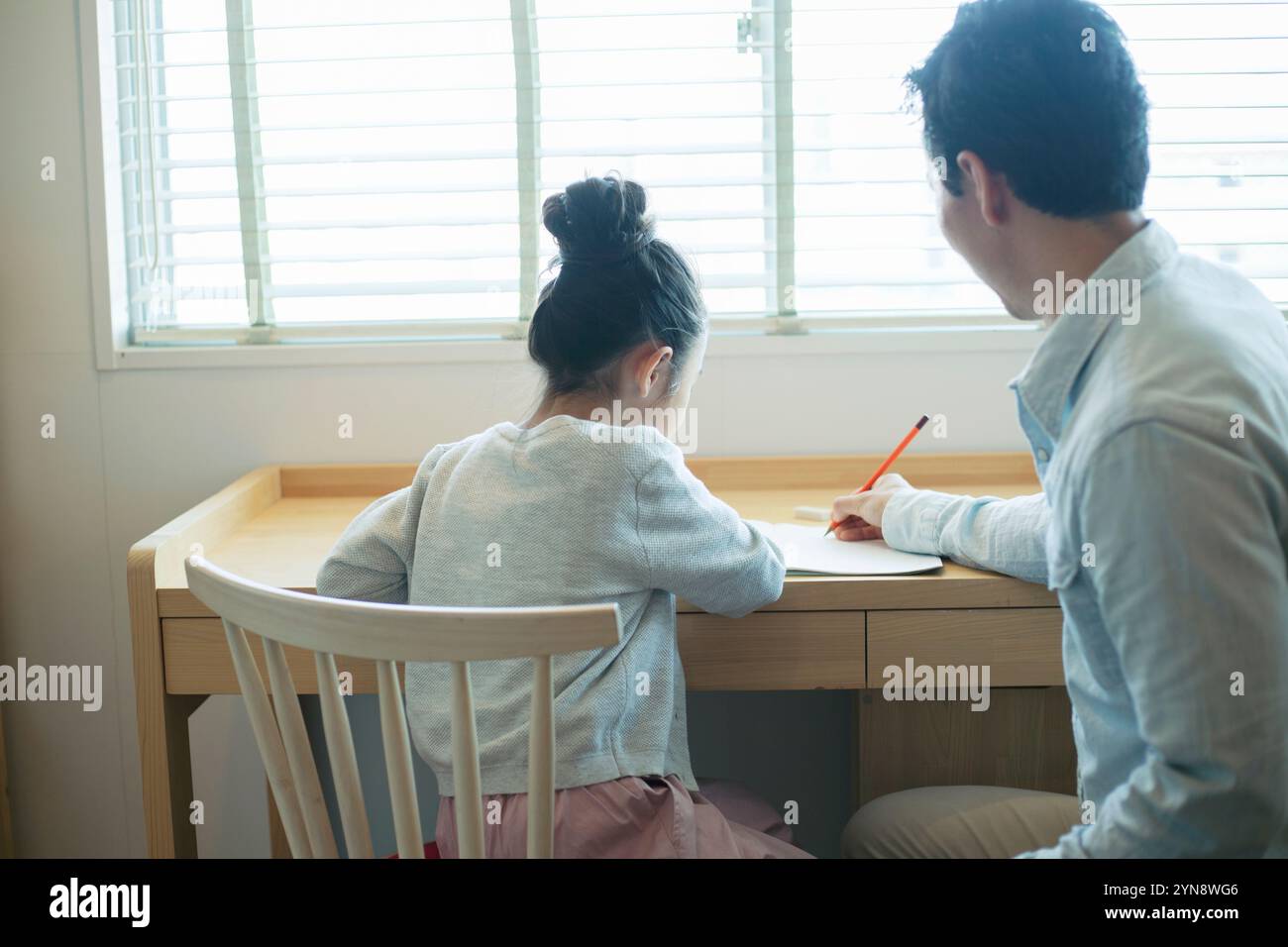 Back view of girl being taught to study in room Stock Photo - Alamy