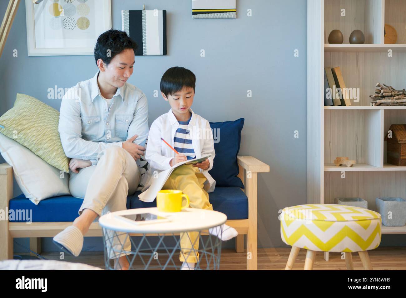 Parent and child sitting on a sofa studying Stock Photo - Alamy