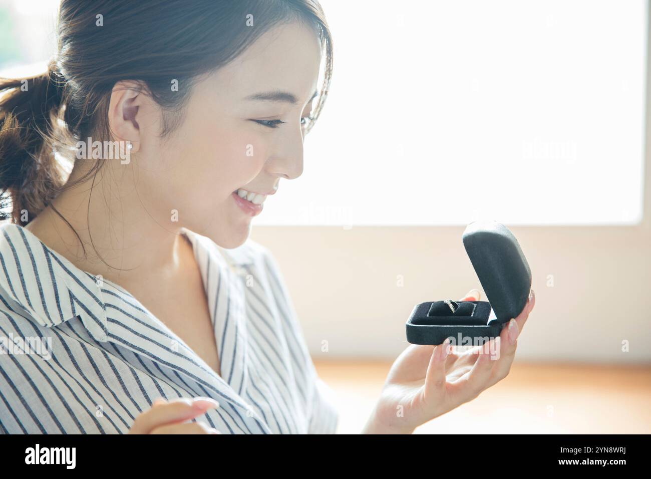 Profile of smiling woman in her 20s looking at rings Stock Photo - Alamy