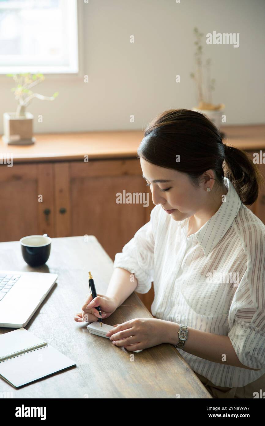 Woman in her 20s writing letters on a memorisation card Stock Photo - Alamy