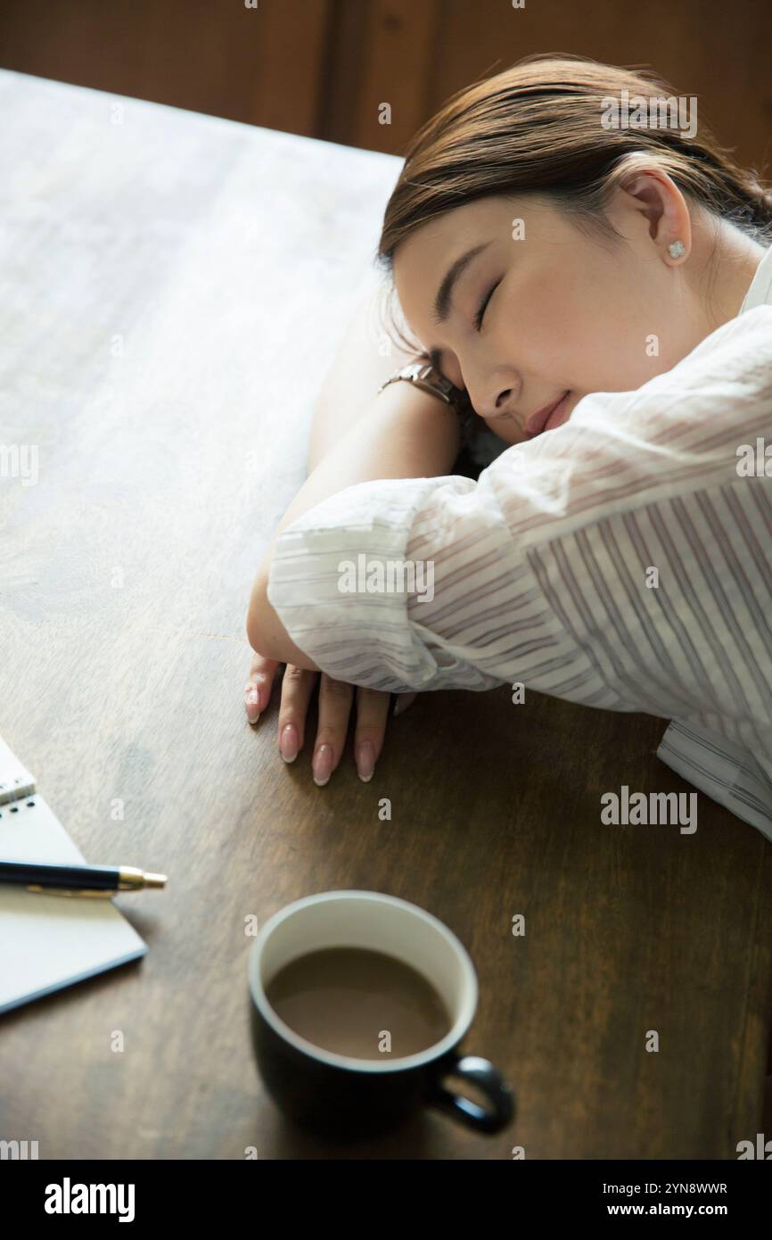 Woman in her 20s leaning against her desk, dozing off Stock Photo - Alamy