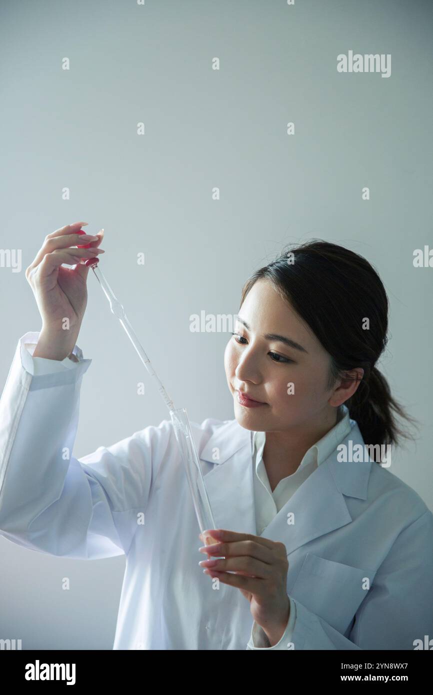 Researcher in her 20s using a dropper to fill a test tube with liquid ...