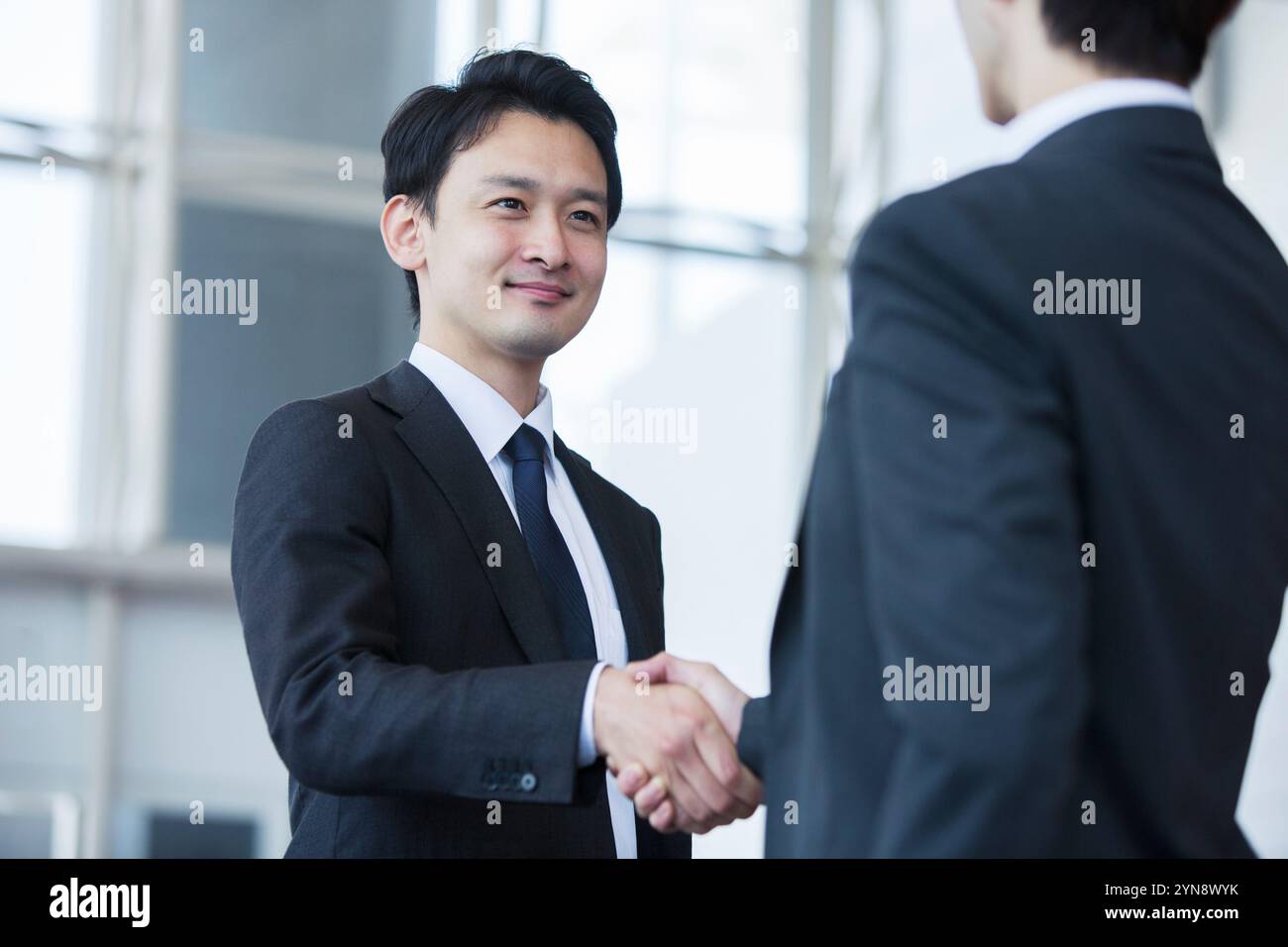 Two men in suits shaking hands Stock Photo - Alamy