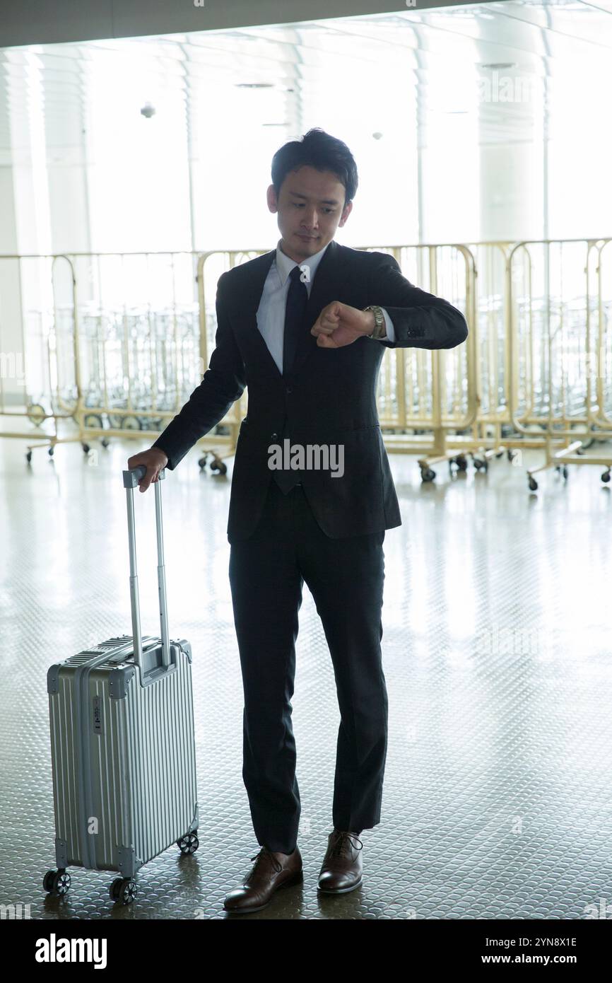 Man in his 20s in a suit checking his watch Stock Photo - Alamy
