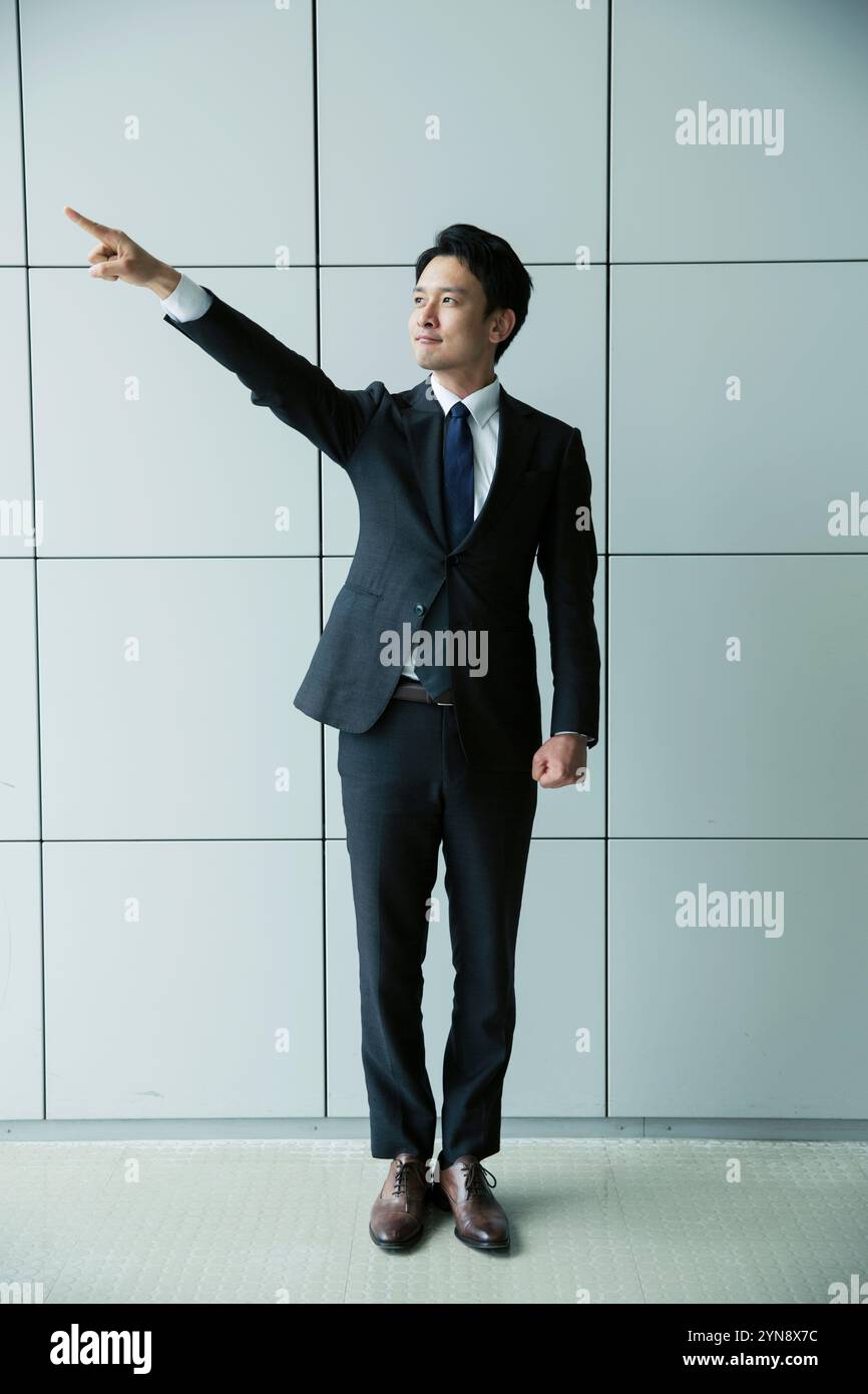 Portrait of man in his 20s in suit pointing and indicating Stock Photo ...