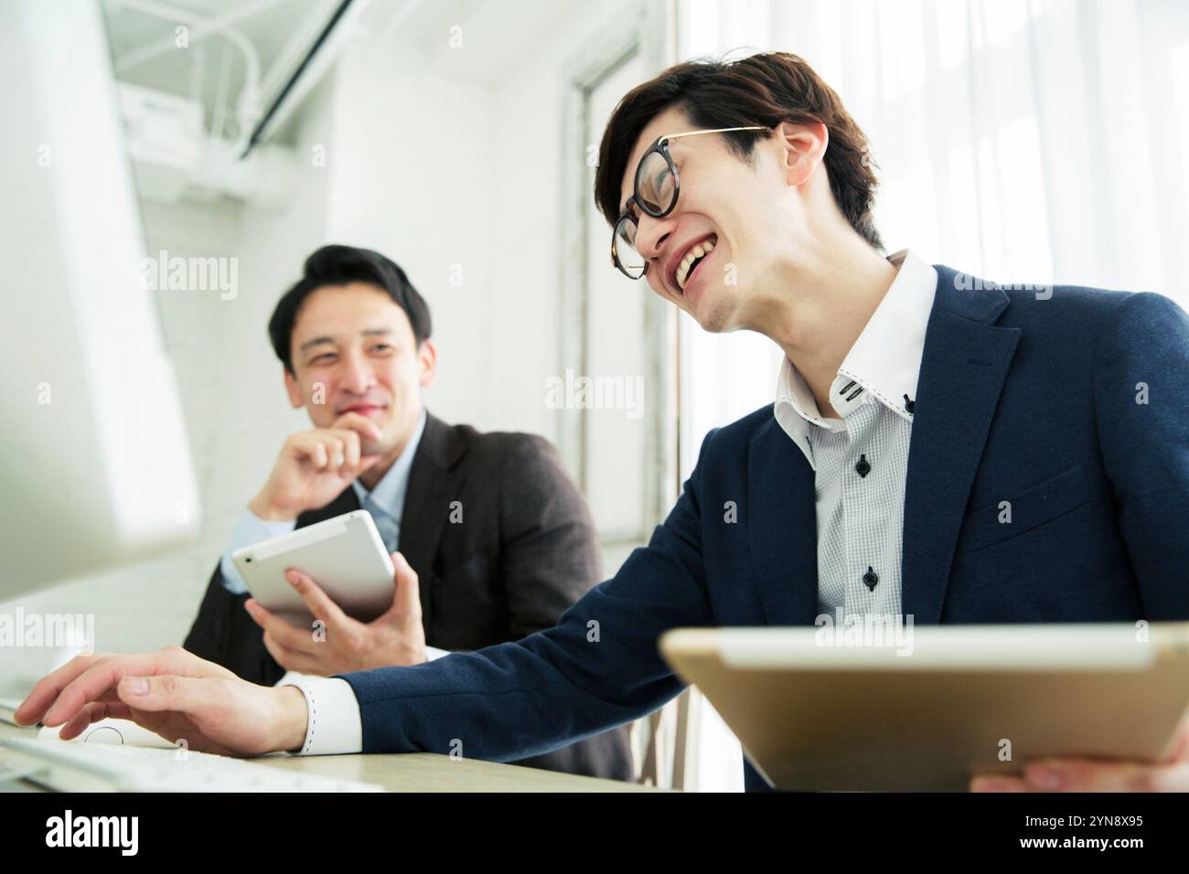 Two men in their 20s working with smiles Stock Photo - Alamy