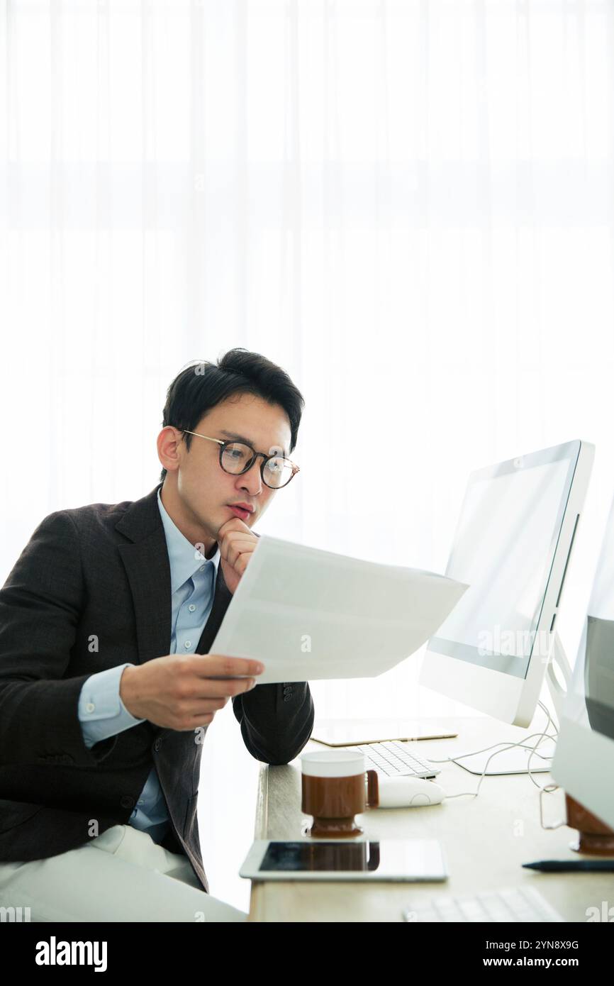 Man in his 20s looking through materials and thinking Stock Photo - Alamy