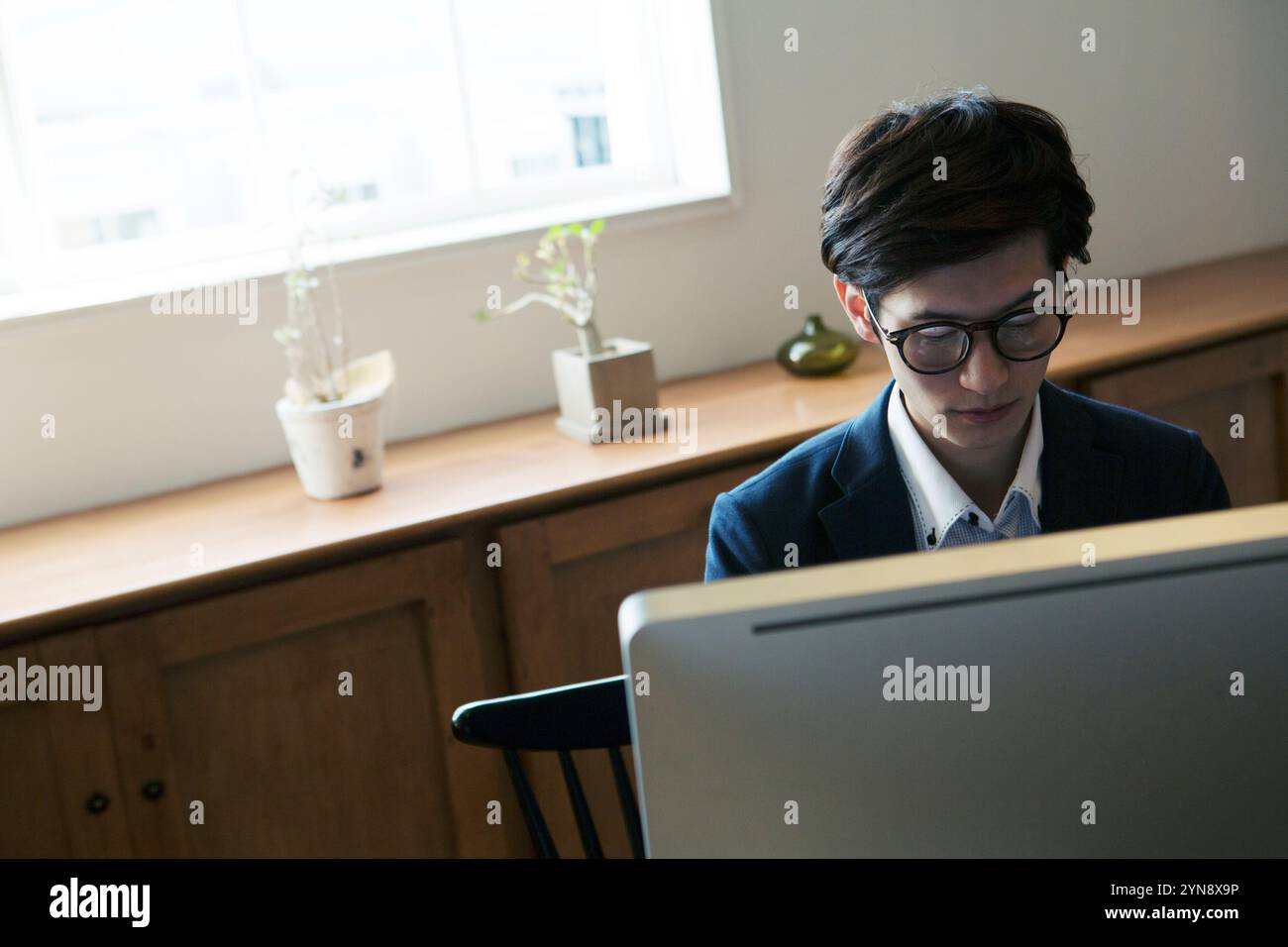 Male in his 20s operating a computer by a window Stock Photo - Alamy