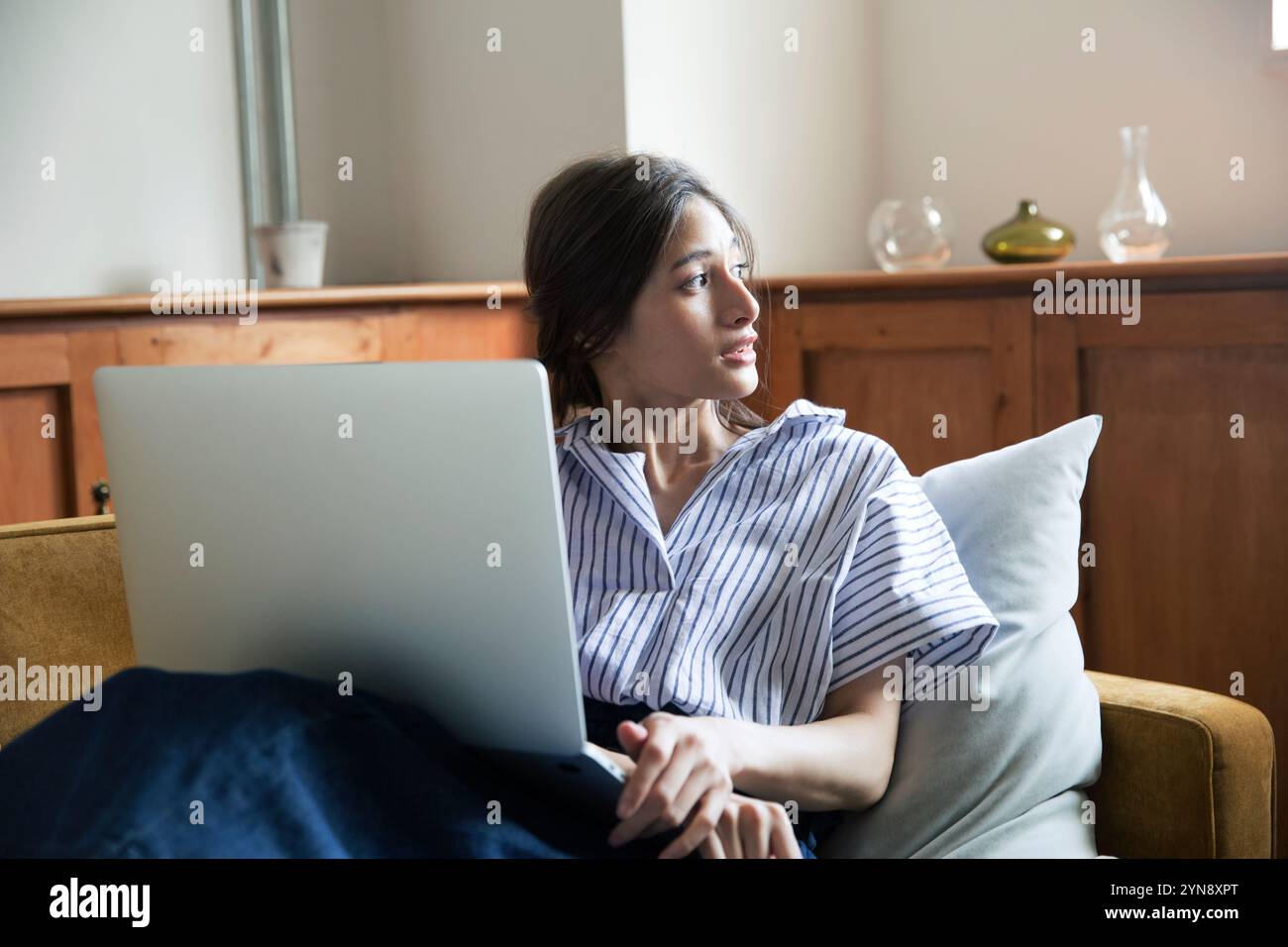 Woman in her 20s with laptop on her lap looking outside Stock Photo - Alamy