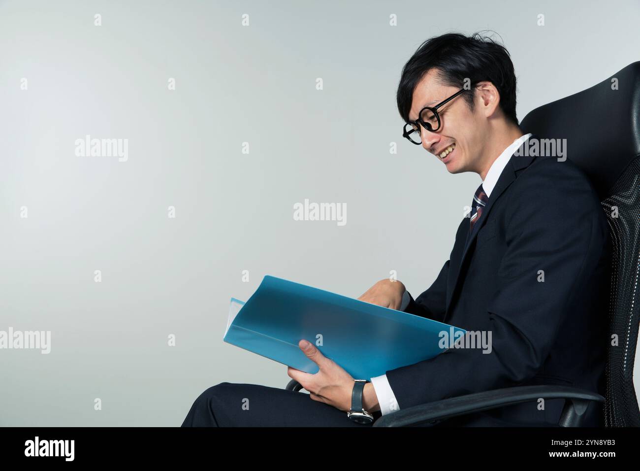 Portrait of man in profile sitting on chair looking at files Stock ...