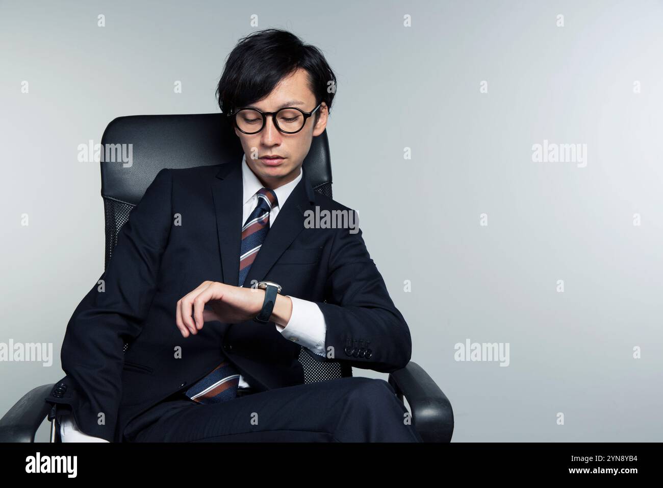 Portrait of man sitting on chair checking watch Stock Photo - Alamy