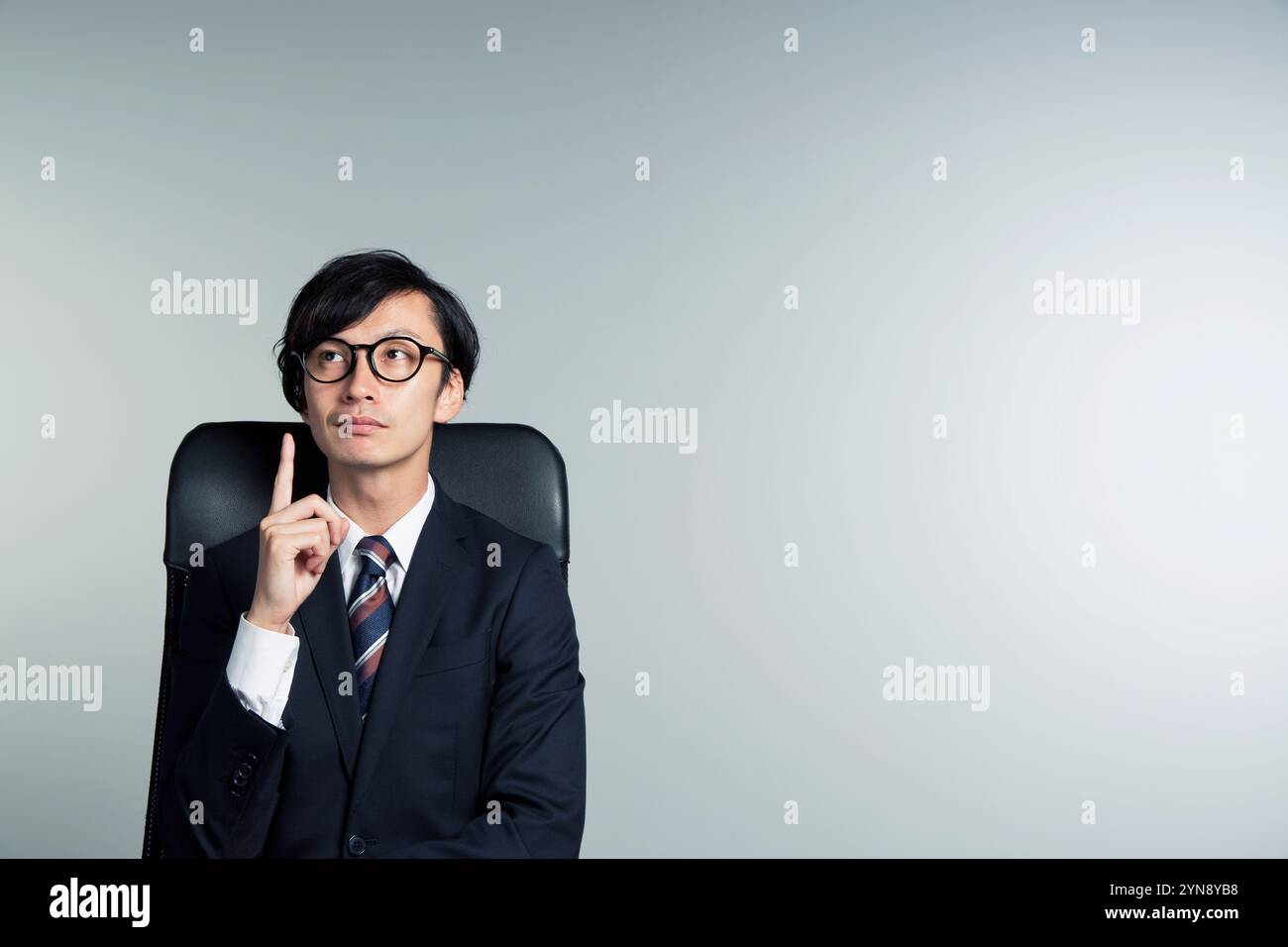 Man sitting on chair holding up index finger Stock Photo - Alamy