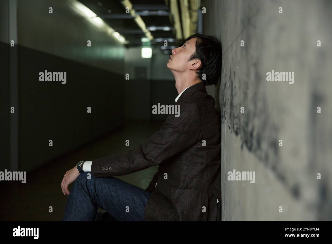 Man crouching and pondering in dark corridor Stock Photo - Alamy
