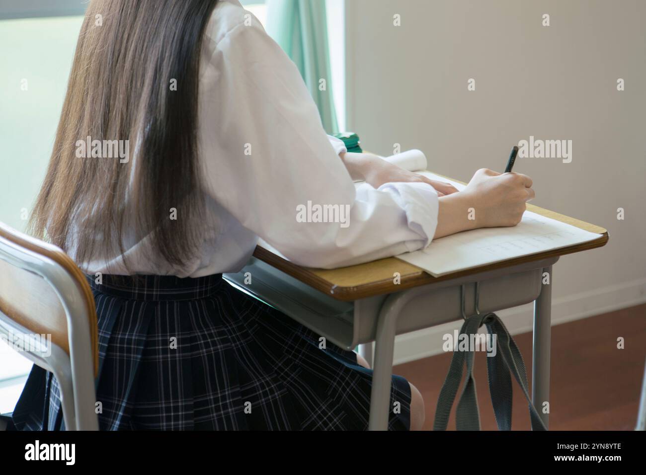 Back view of female high school student taking notes using pencil Stock ...