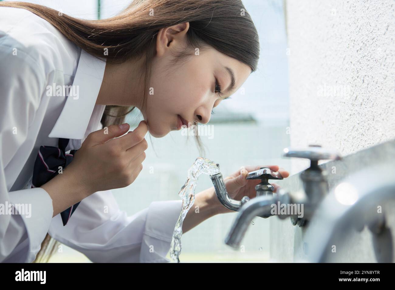 High school girl drinking water coming out of a tap Stock Photo - Alamy