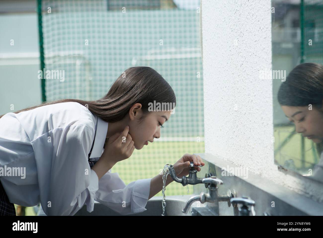 High school girl drinking water coming out of a tap Stock Photo - Alamy