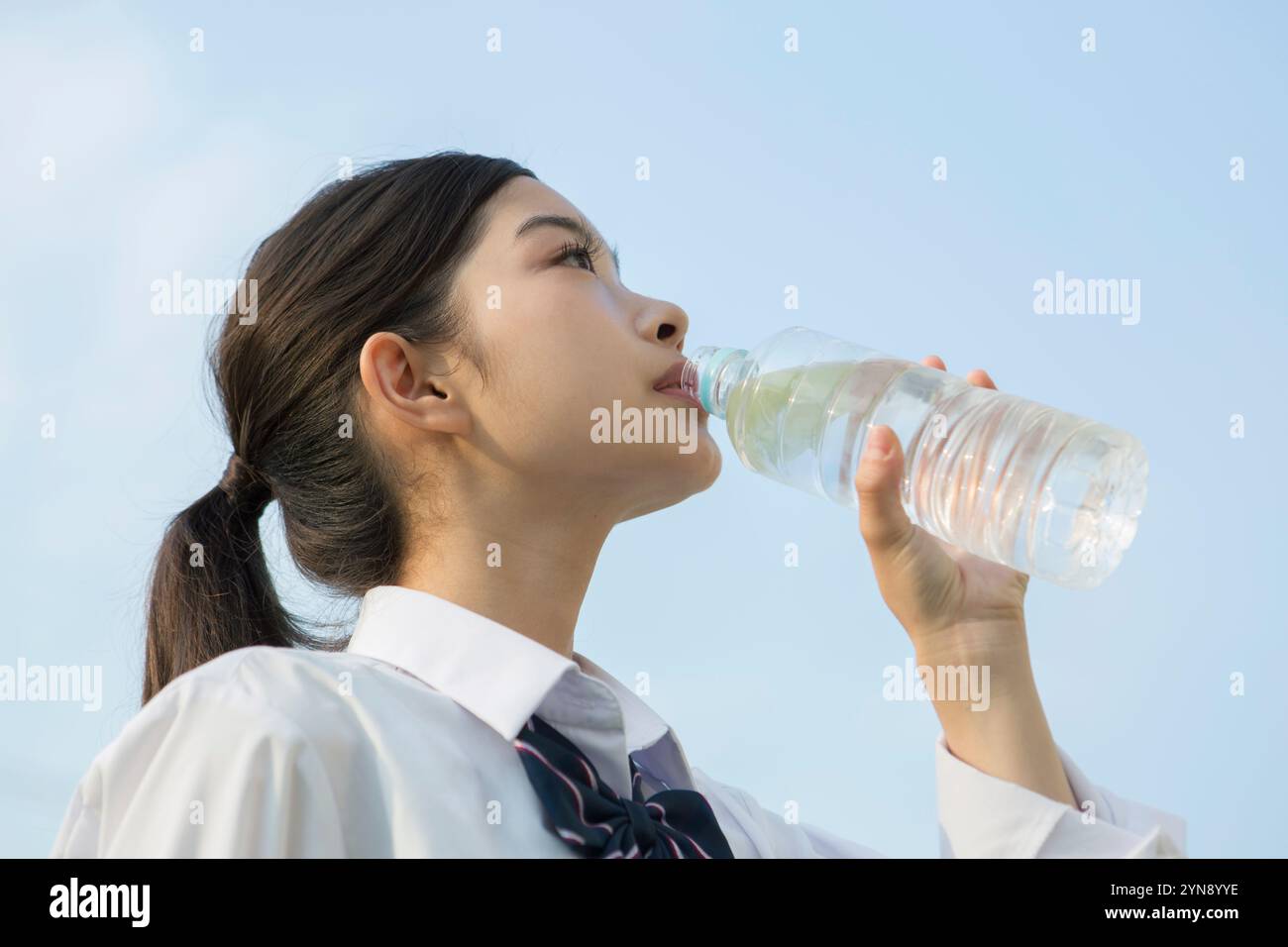 High school girl drinking water from a plastic bottle under a blue sky Stock Photo - Alamy