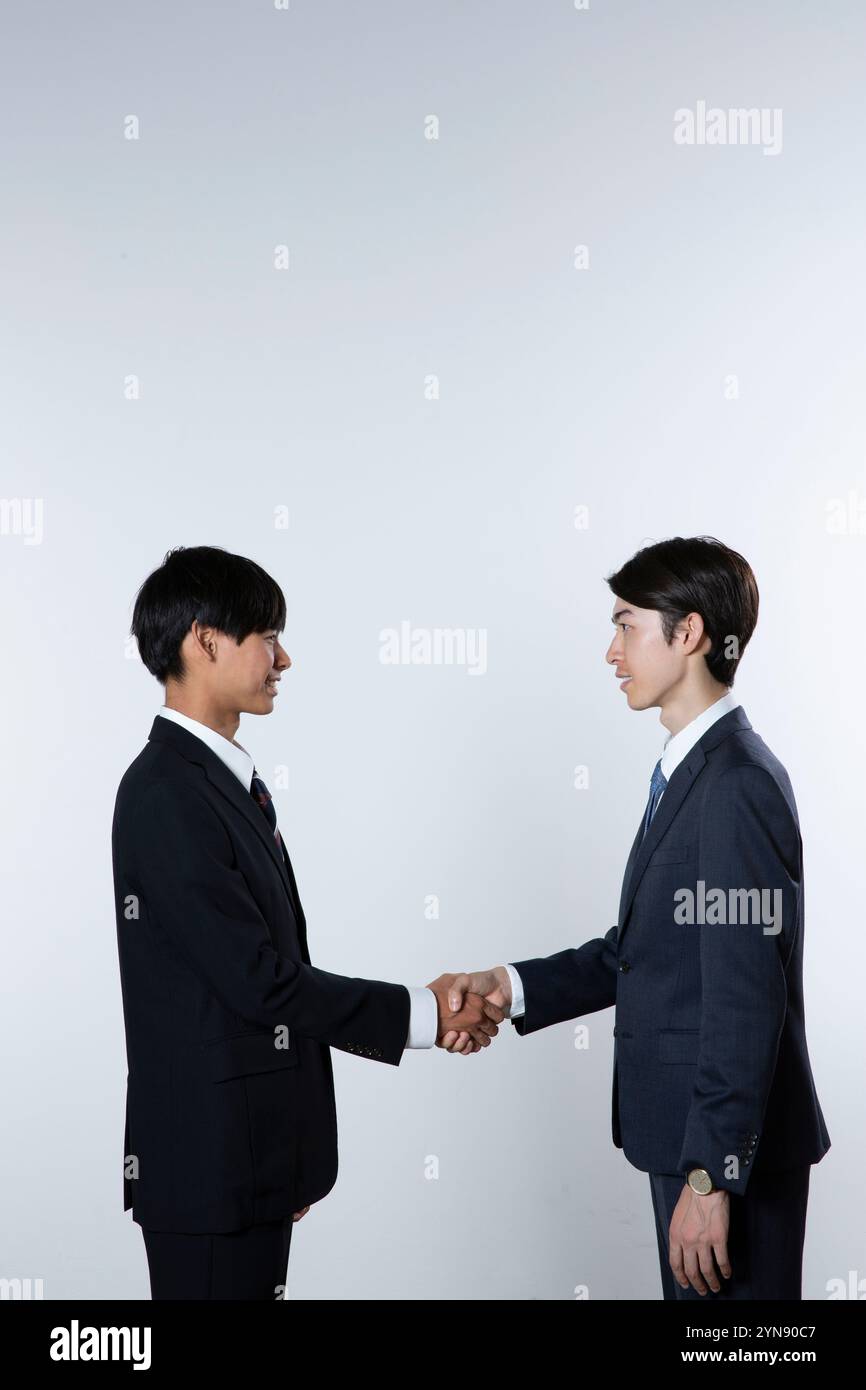 Two men in their 20s in suits shaking hands Stock Photo - Alamy