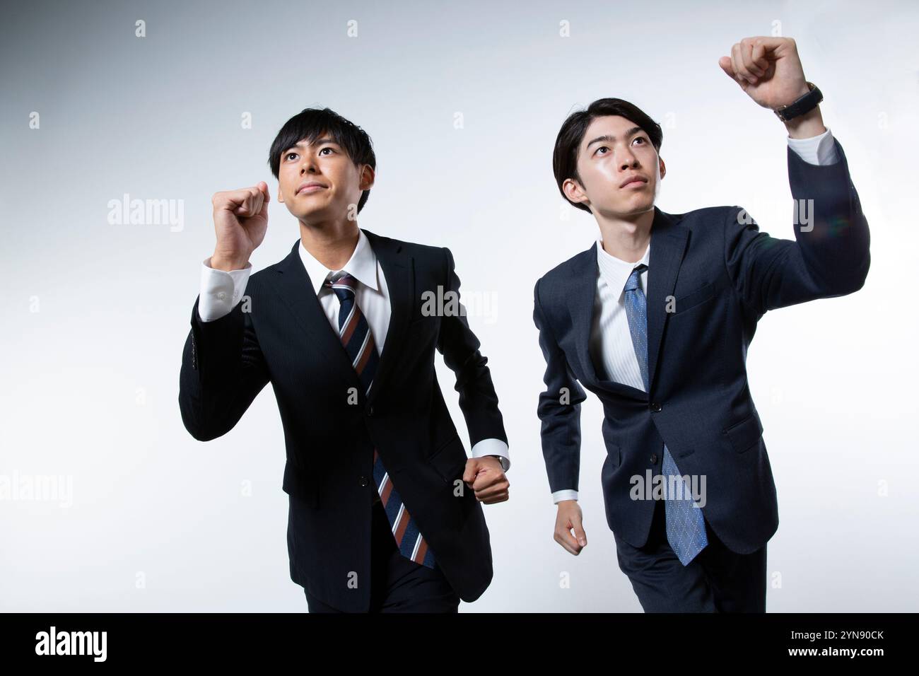 Portrait of two men in their 20s in suits running to work Stock Photo ...