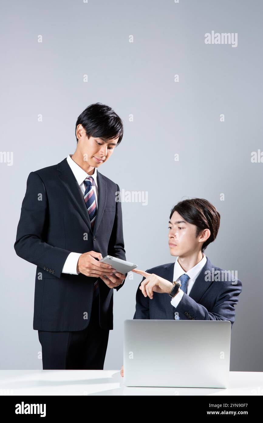 Two men in suits showing and explaining the tablet Stock Photo - Alamy