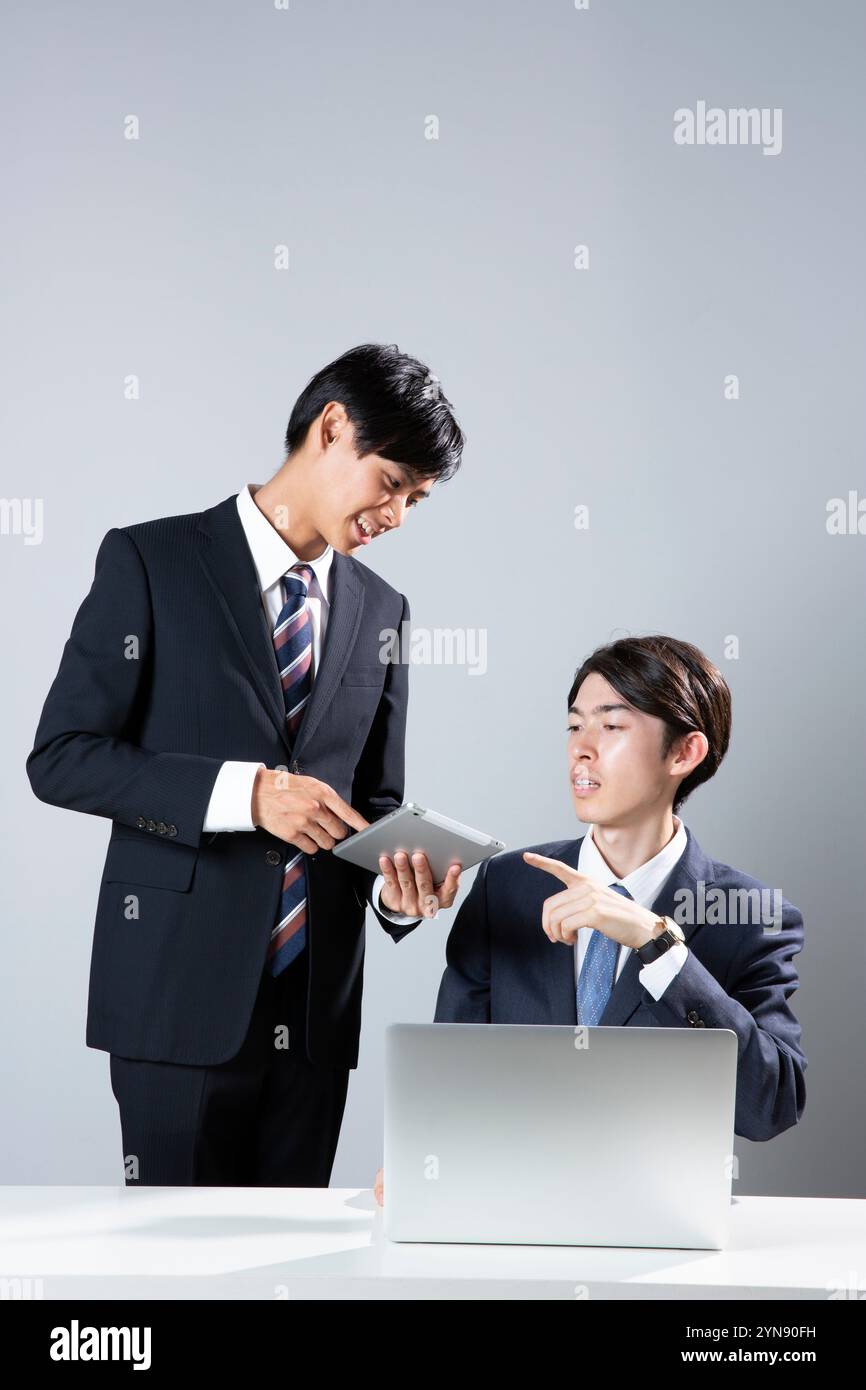 Two men in suits showing and explaining the tablet Stock Photo - Alamy