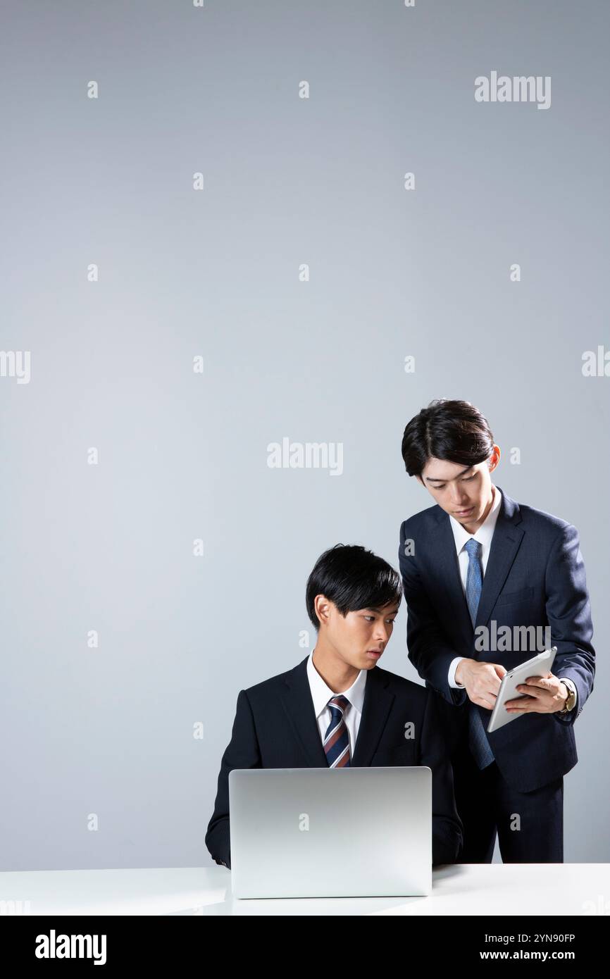 Two men in suits showing and explaining the tablet Stock Photo - Alamy