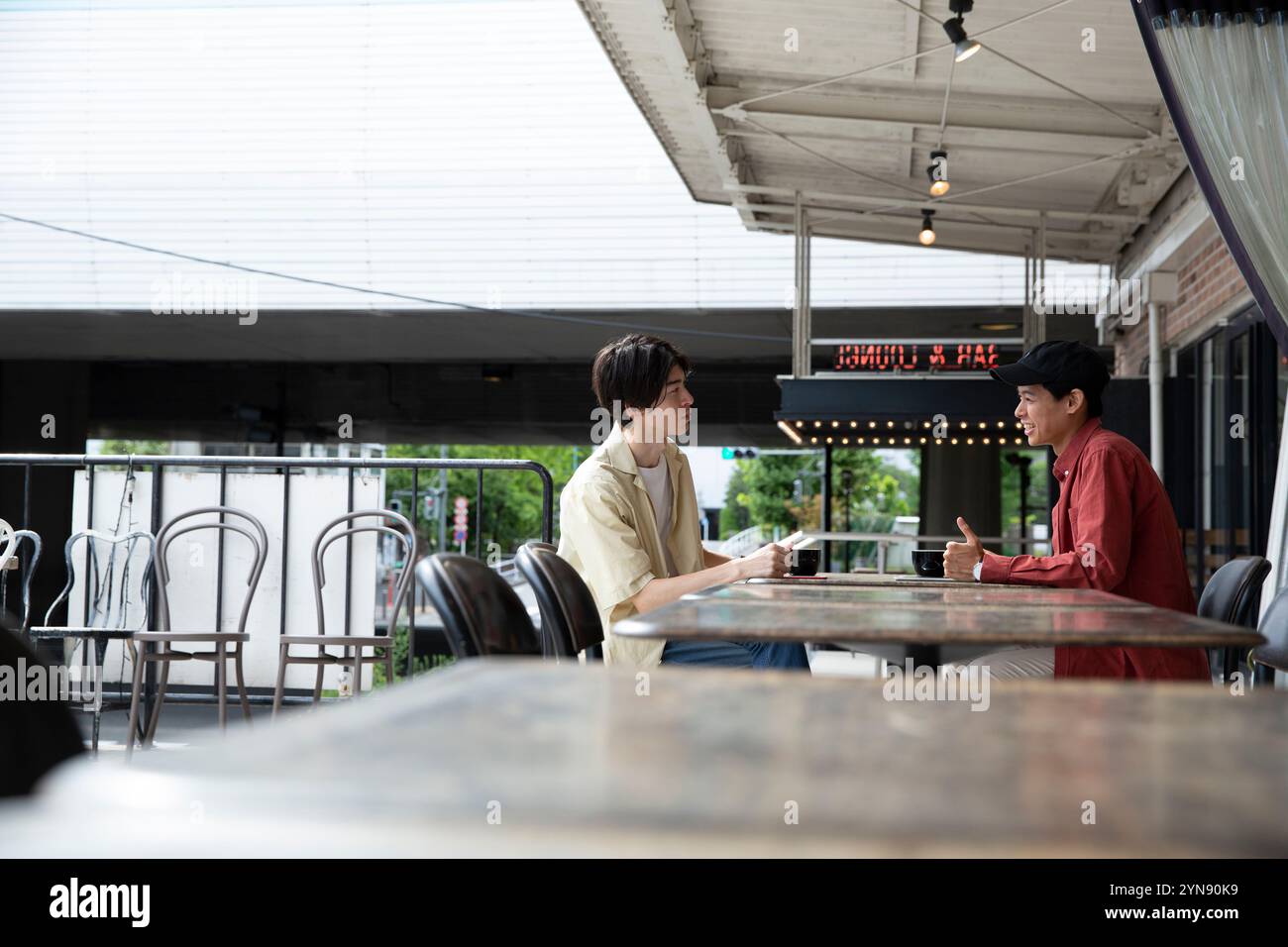 Two men in their 20s talking at a café Stock Photo - Alamy