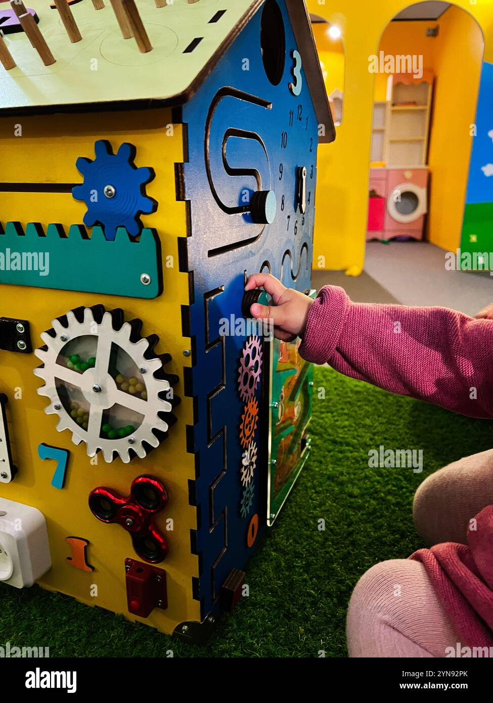 A child engages with a colorful educational activity board full of ...