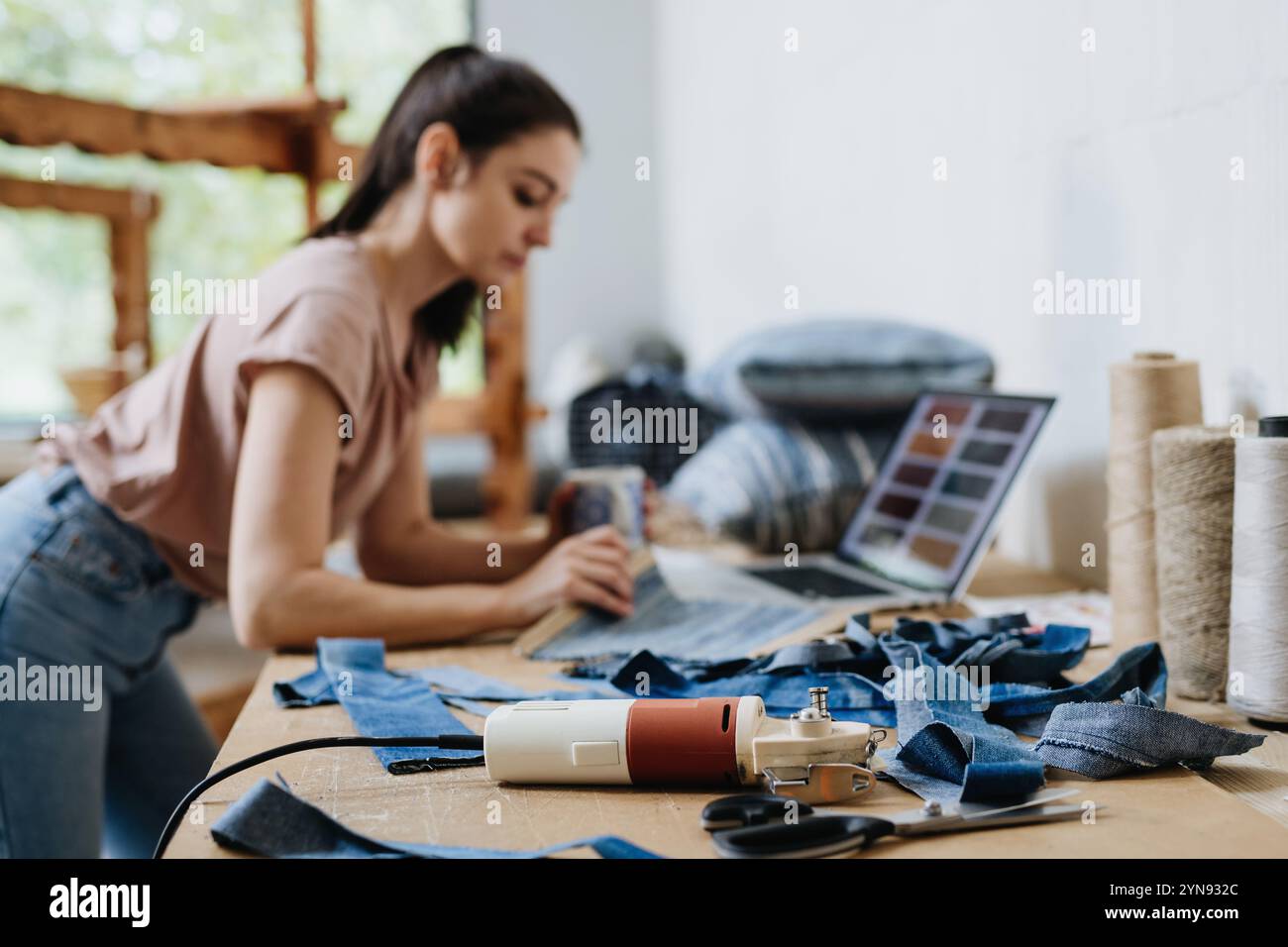 Young businesswoman working on laptop on workbench, standing by wooden ...