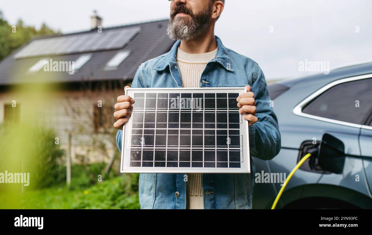Man holding model of solar panel in hands. Charging electric car and ...