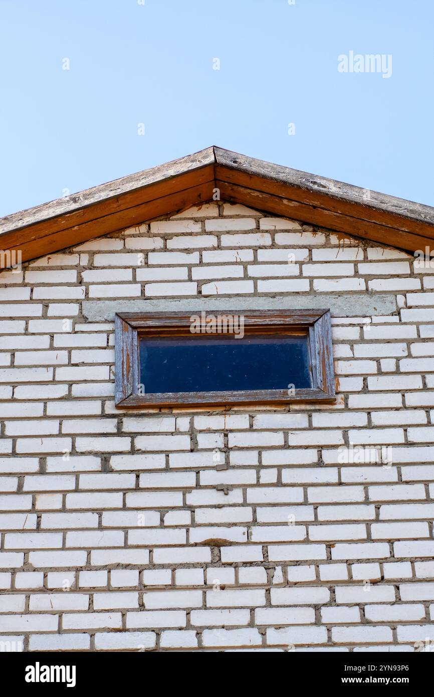 The sloped roof of a charming white brick building features a small ...
