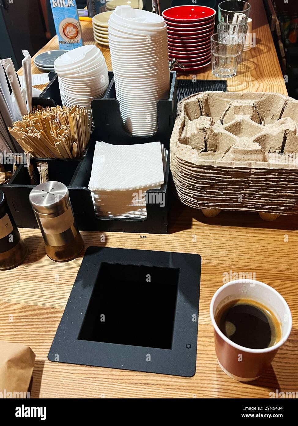 A coffee shop counter featuring disposable cups, lids, stirrers, and ...