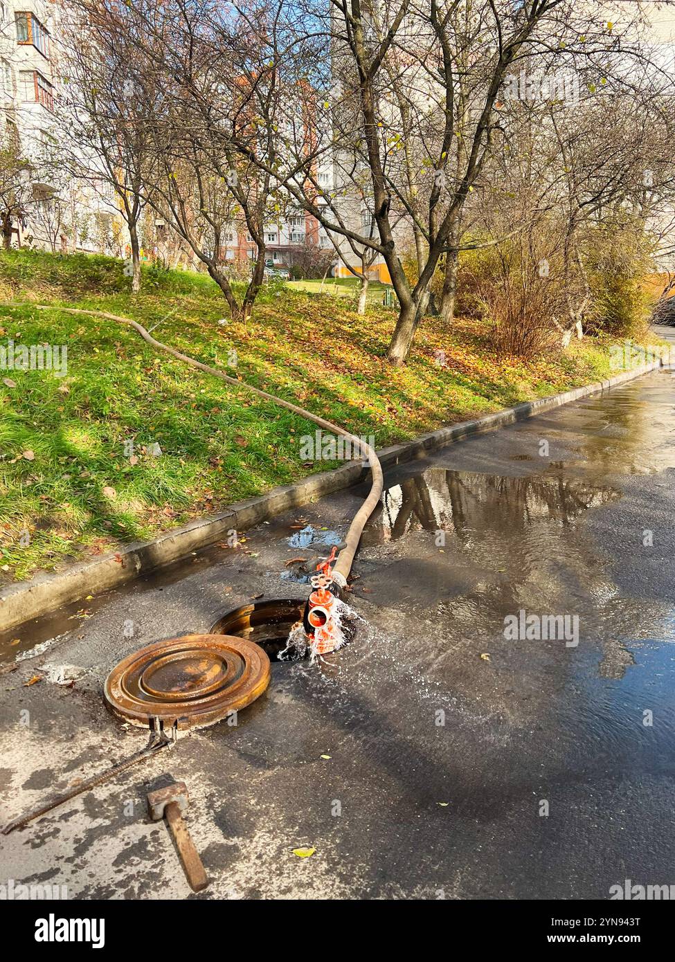 A city street scene showing an open manhole with water leaking from a ...