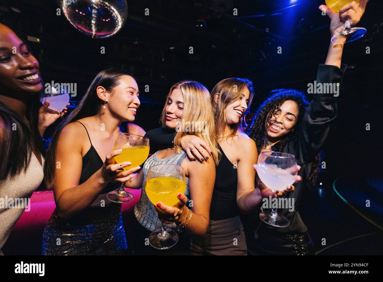 A group of friends celebrates on a fun night out at a vibrant nightclub ...