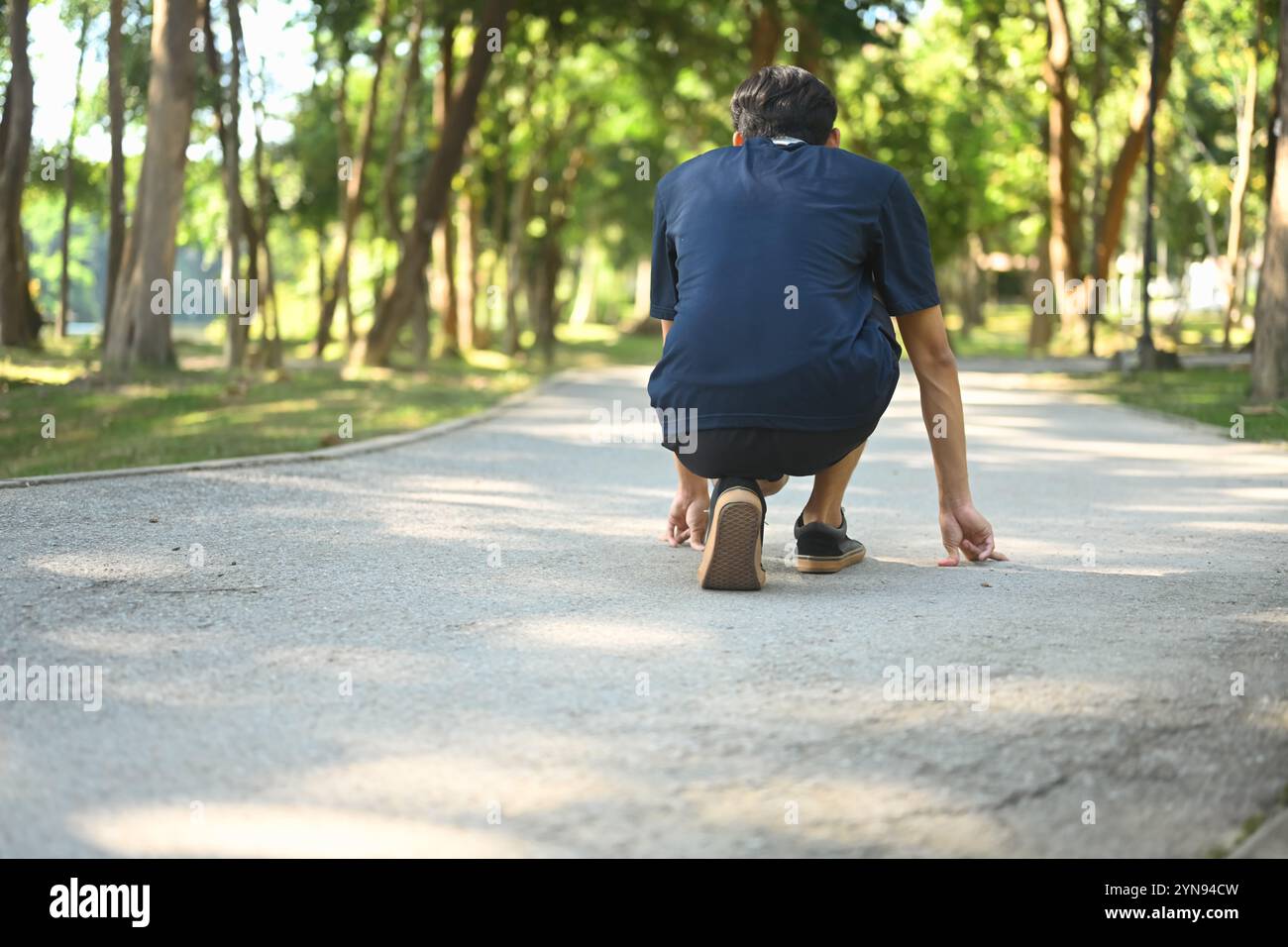 Back view of man in a starting position on the ground, ready to sprint ...