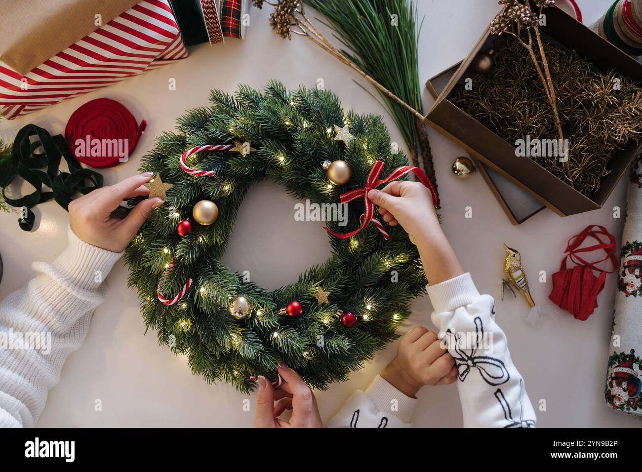 Top view of mom and daughter decorating Christmas wreath. Process of ...
