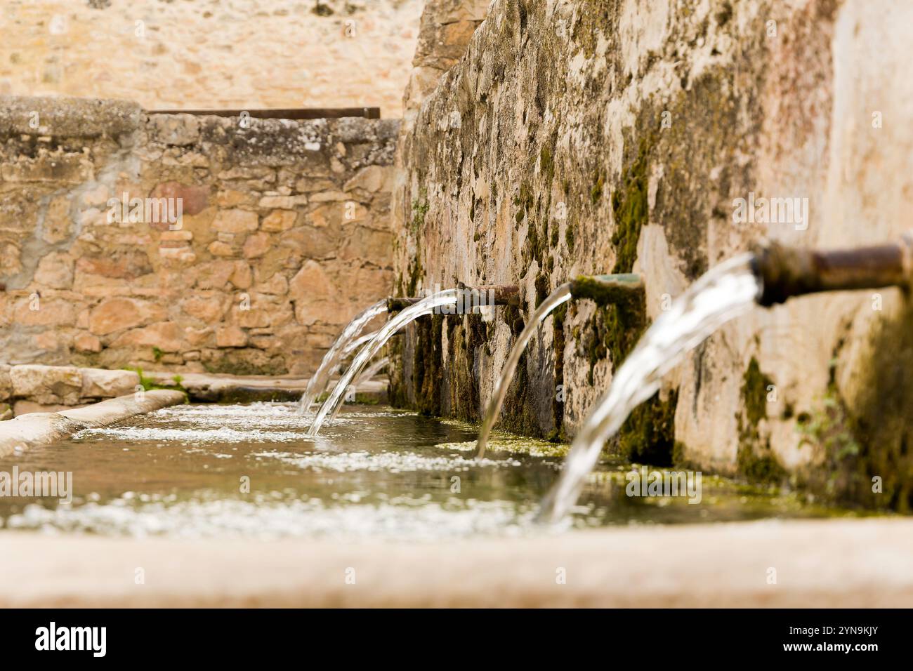 Five water spouts are spraying water into a pool. The water is clear ...