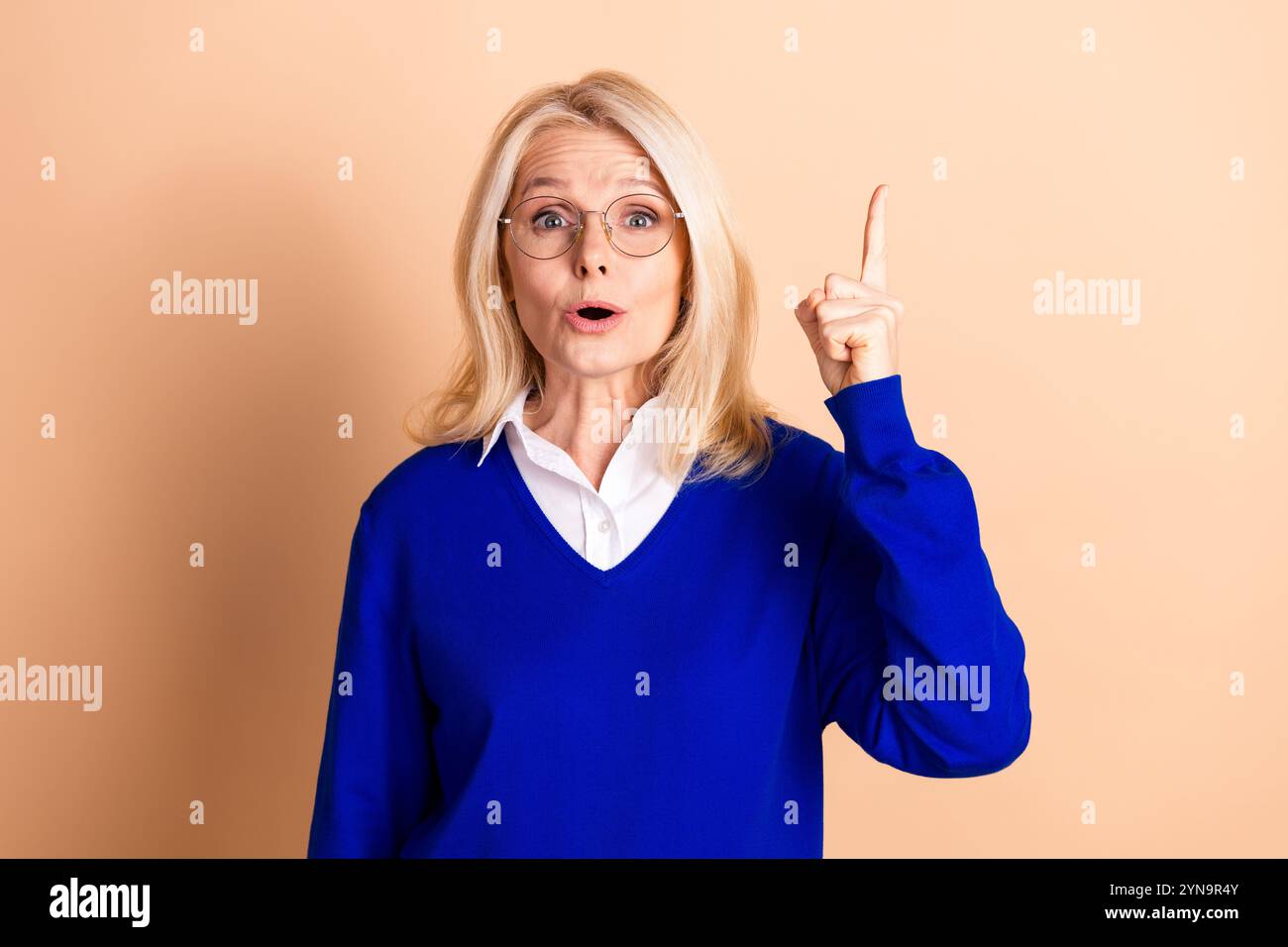 Elegant senior woman in blue jumper making a point with raised finger ...