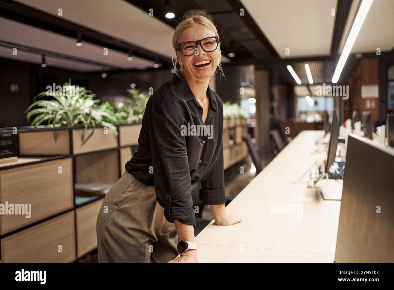 A Smiling Woman Standing Joyfully at a Modern Office Reception Desk ...