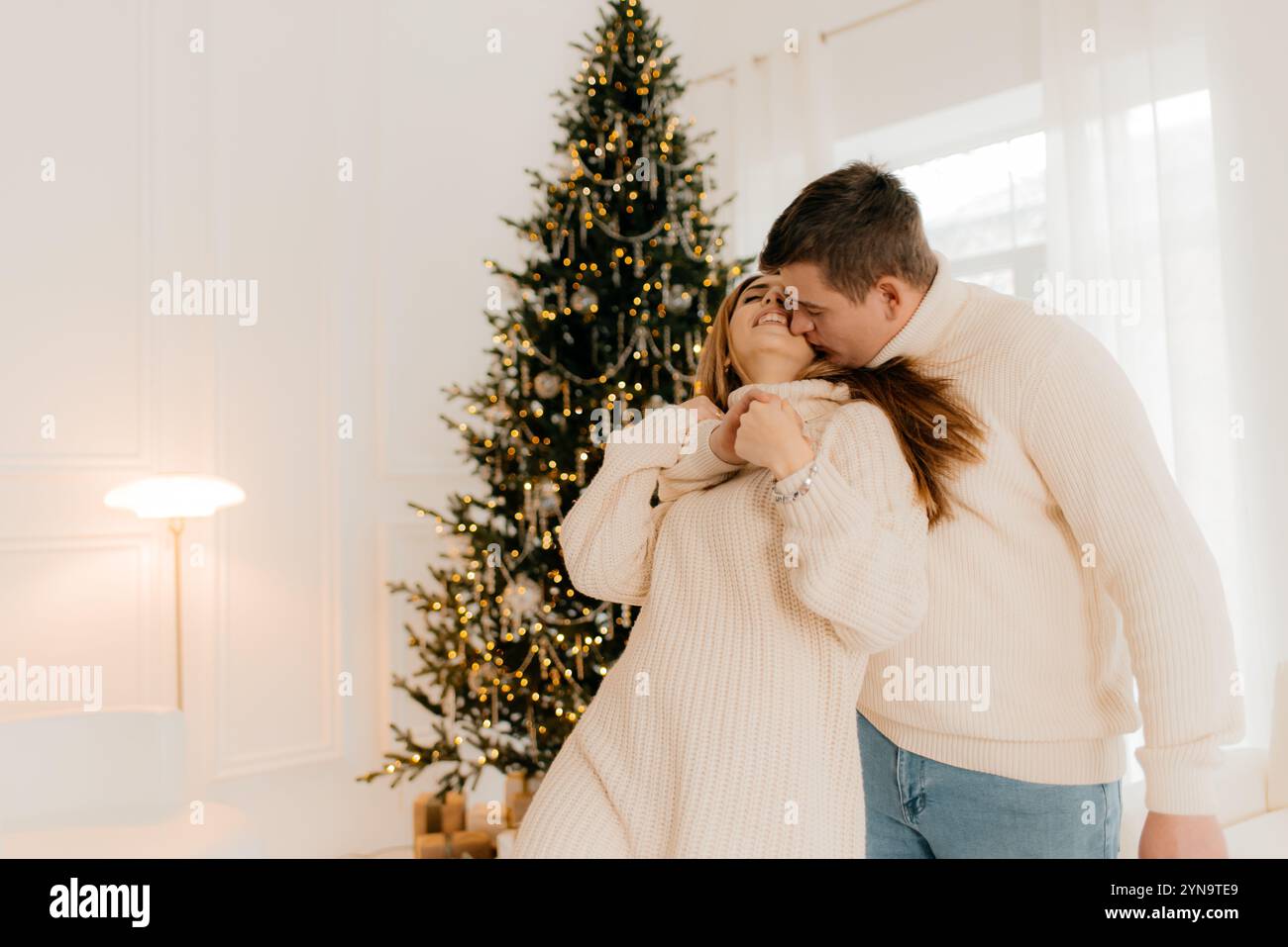 Picture showing young couple hugging over Christmas tree Stock Photo ...