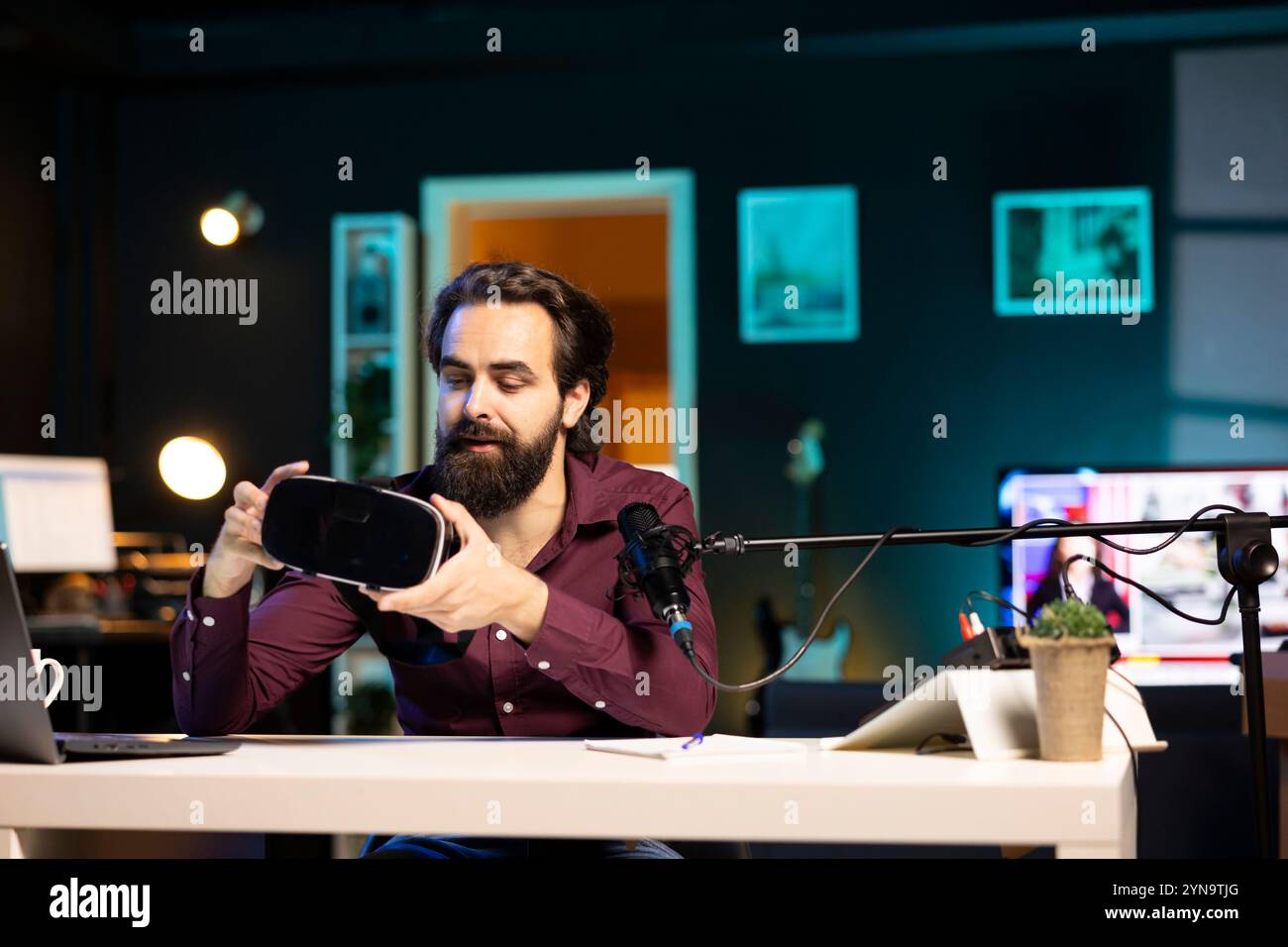 Tech vlogger reviewing VR goggles in rgb lights living room studio ...