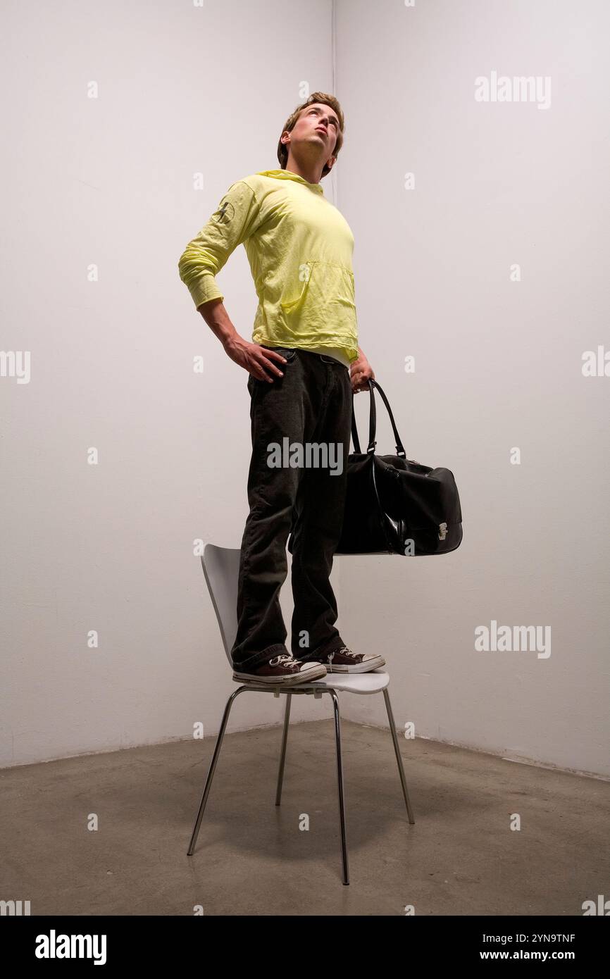 A male model standing on a chair during a photo shoot at a studio in ...