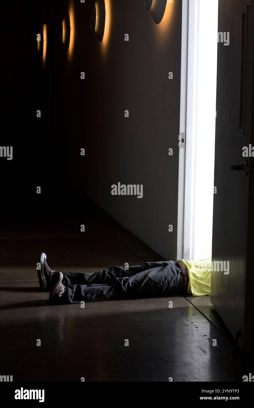 A male model lying down between a doorway during a photo shoot at a ...